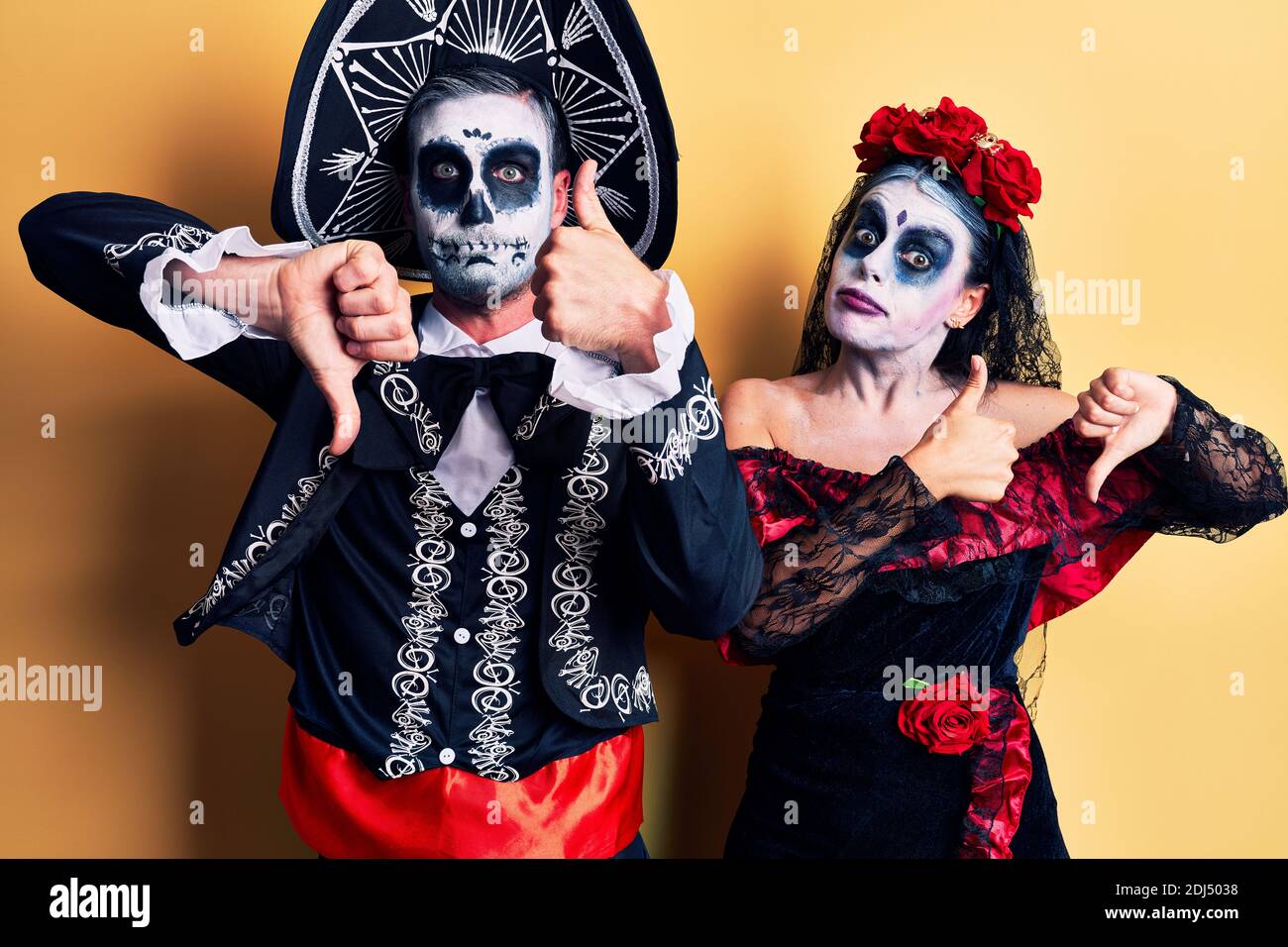Young couple wearing mexican day of the dead costume over yellow doing ...