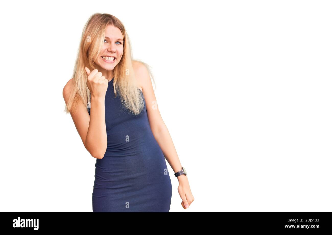 Young beautiful blonde woman wearing casual dress angry and mad raising ...