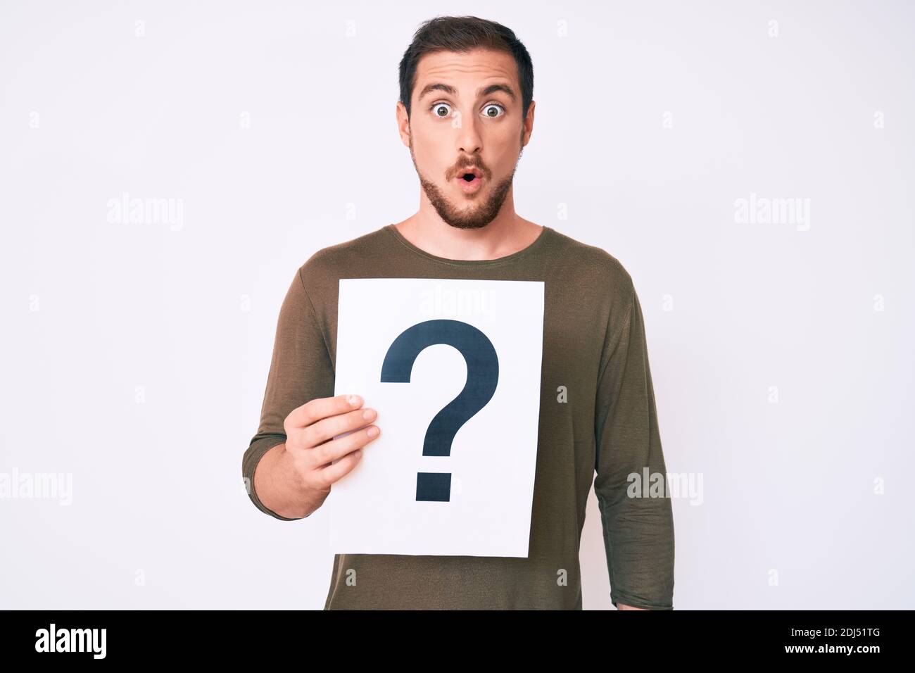 Young handsome man holding question mark scared and amazed with open ...