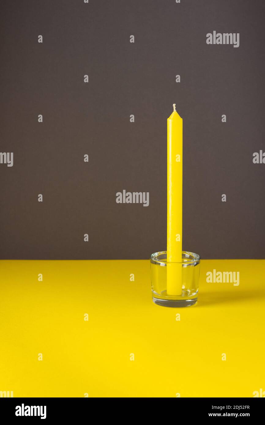 Yellow tall candle in a glass candlestick, trendy colors of the year ...