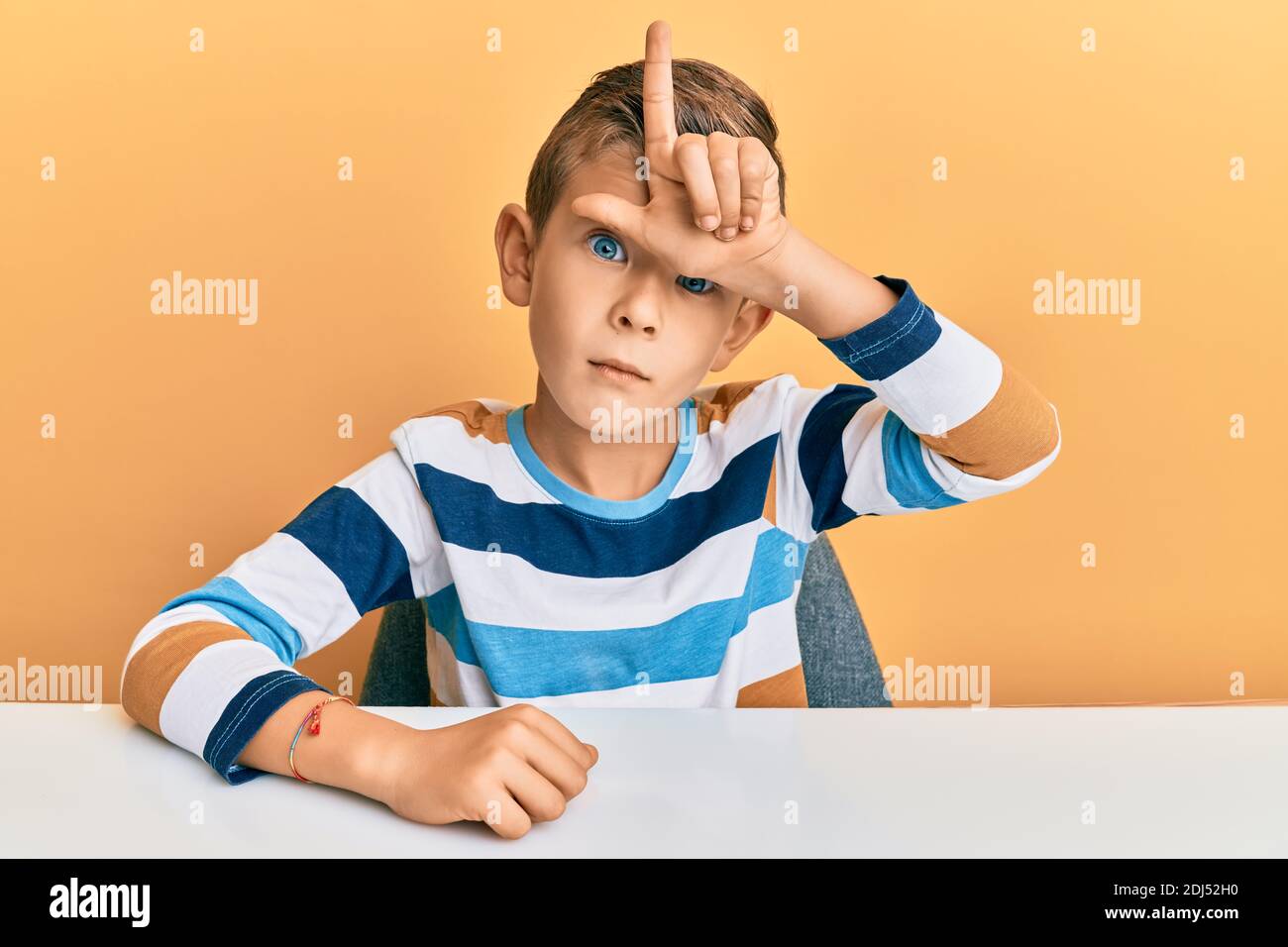 Adorable caucasian kid wearing casual clothes sitting on the table ...