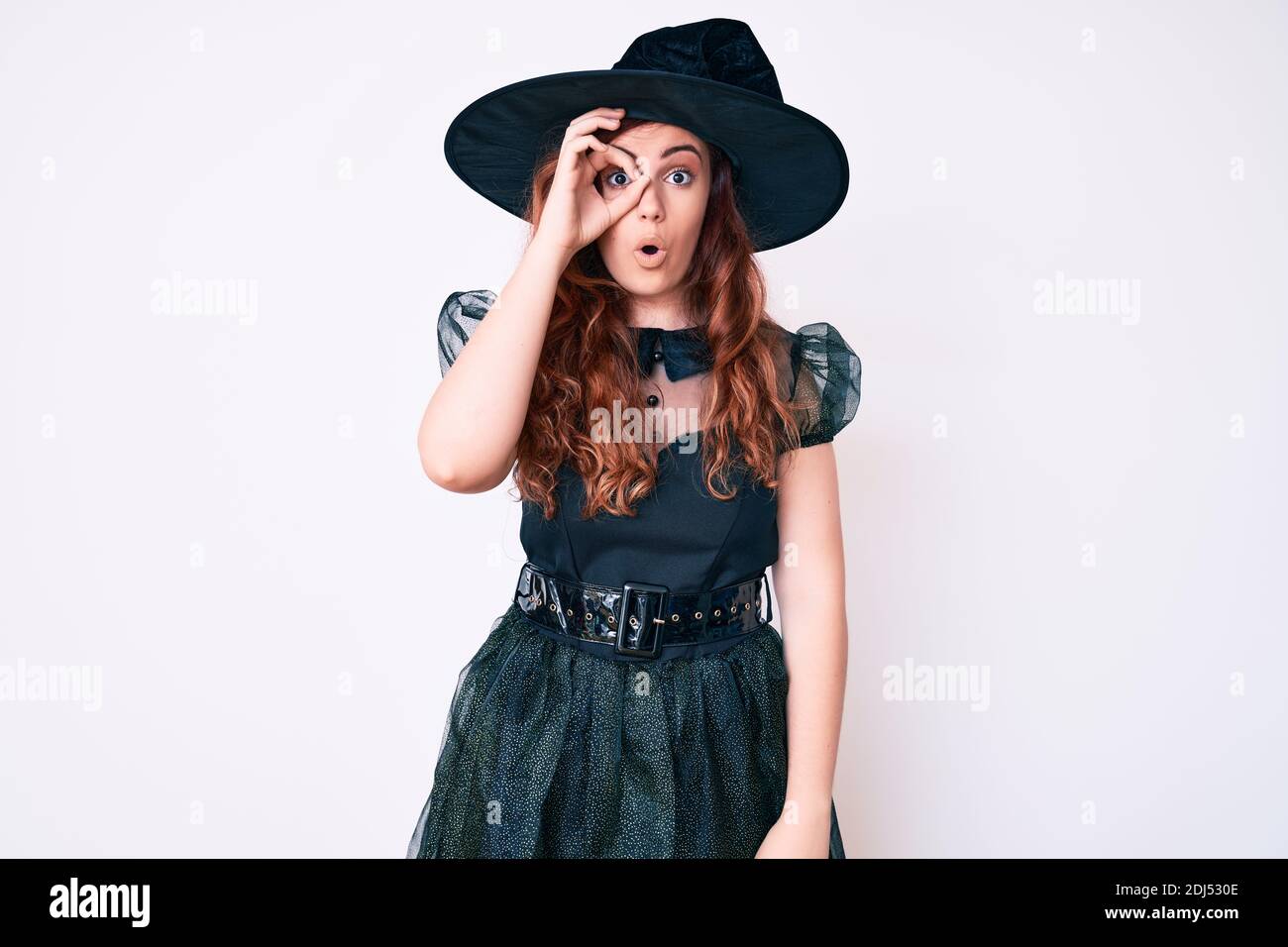 Young beautiful woman wearing witch halloween costume doing ok gesture ...