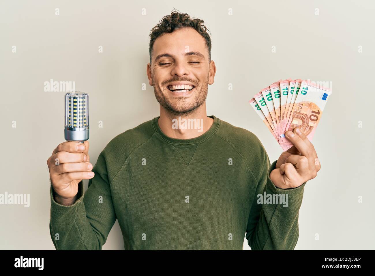 Young hispanic man holding led bulb and euros banknotes smiling and ...