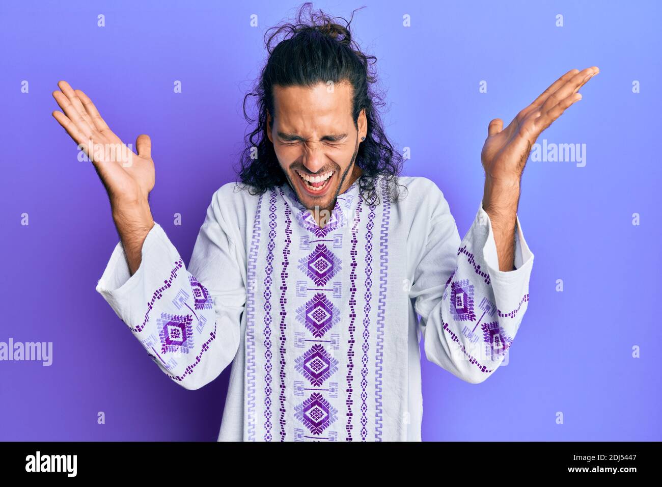 Young handsome man with long hair wearing bohemian and hippie shirt ...