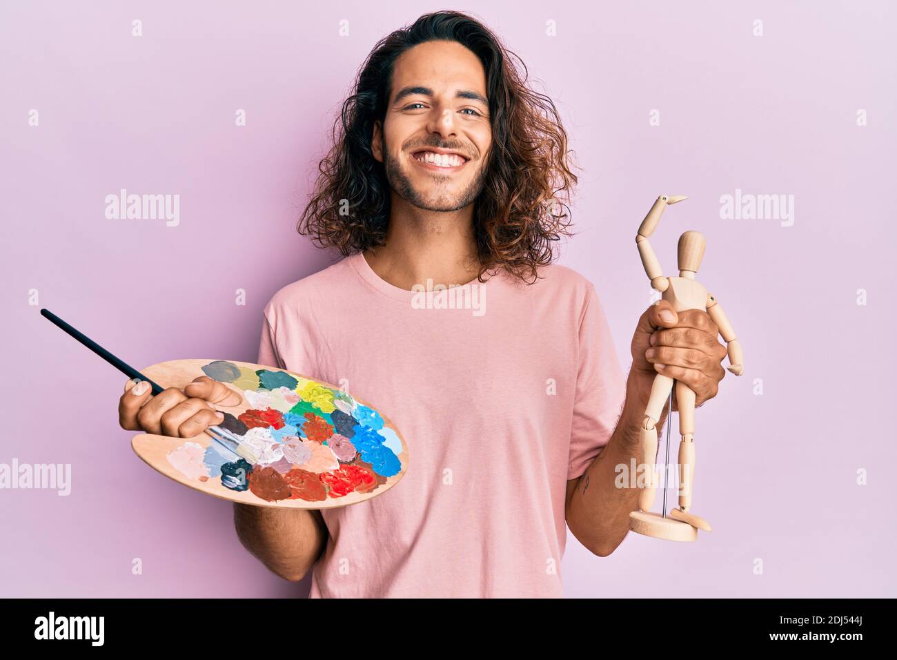 Young handsome man with long hair holding painter palette and art ...
