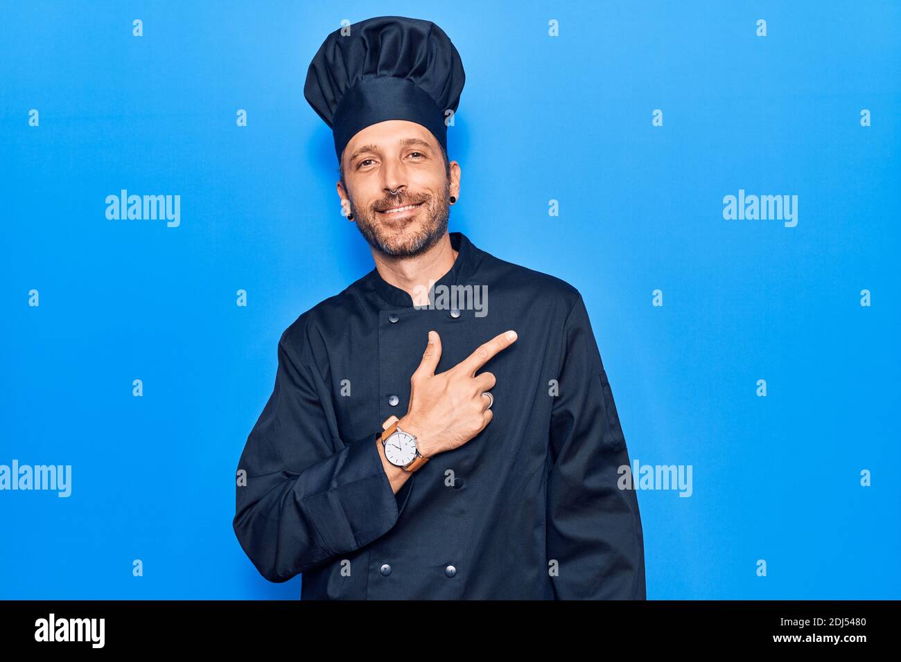 Young handsome man wearing cooker uniform smiling cheerful pointing ...