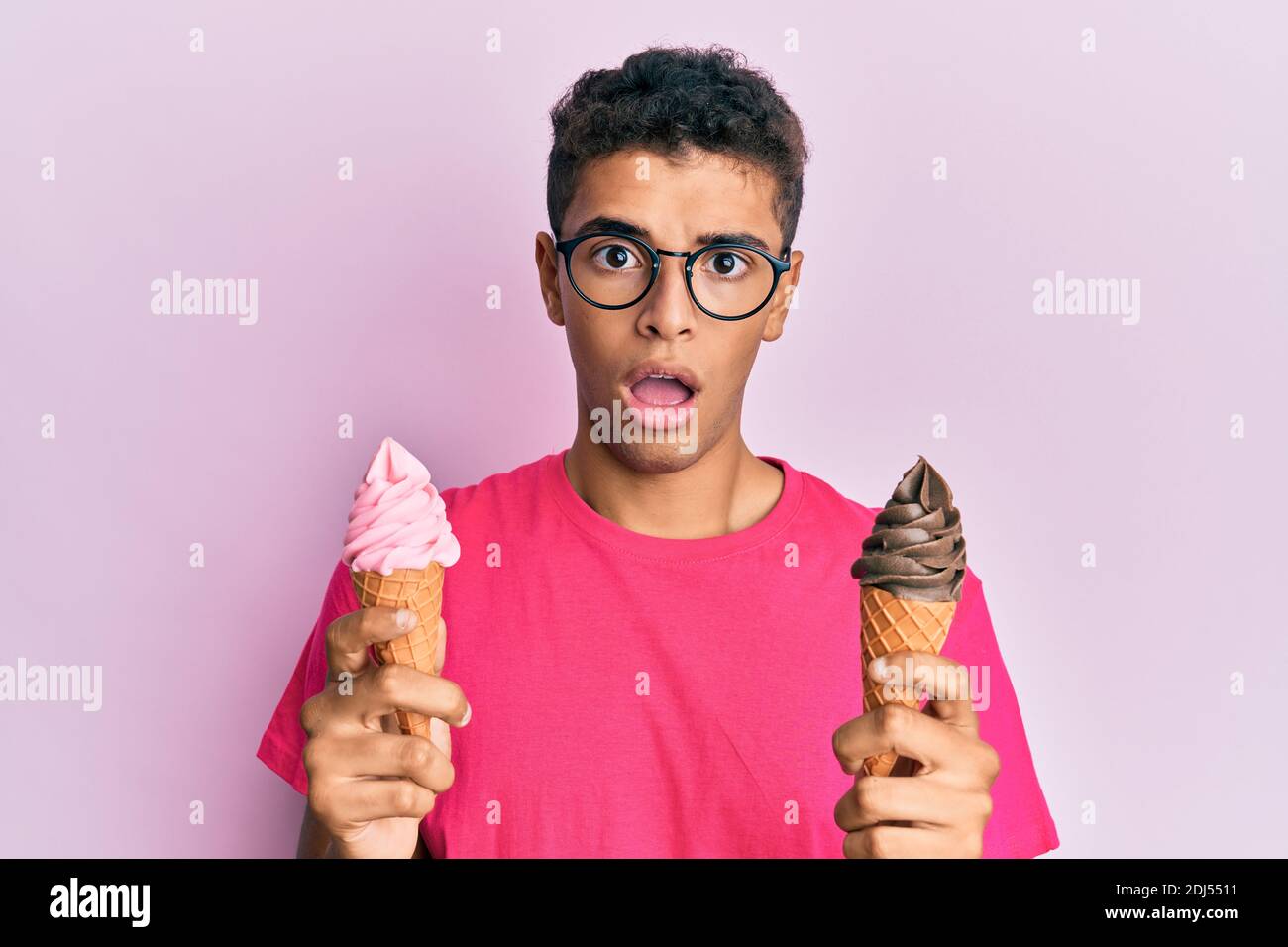 Young handsome african american man holding ice cream cones in shock ...
