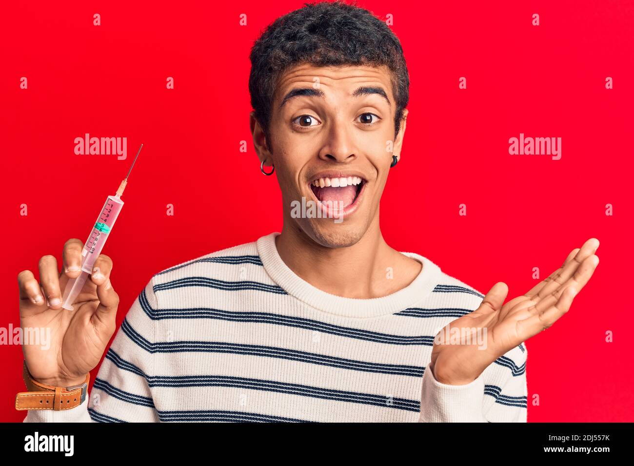 Young african amercian man holding syringe celebrating achievement with ...