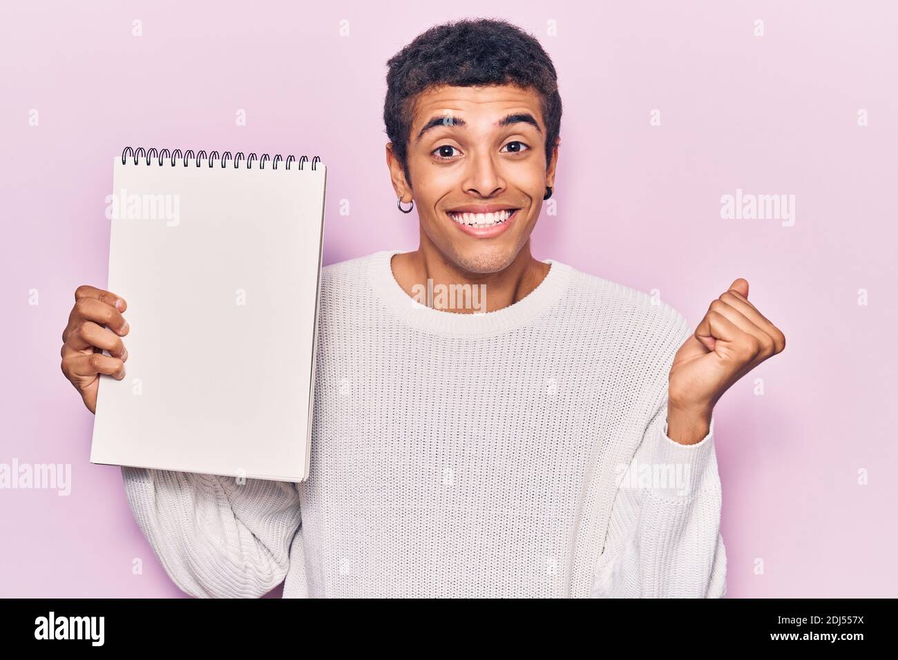 Young african amercian man holding notebook screaming proud ...