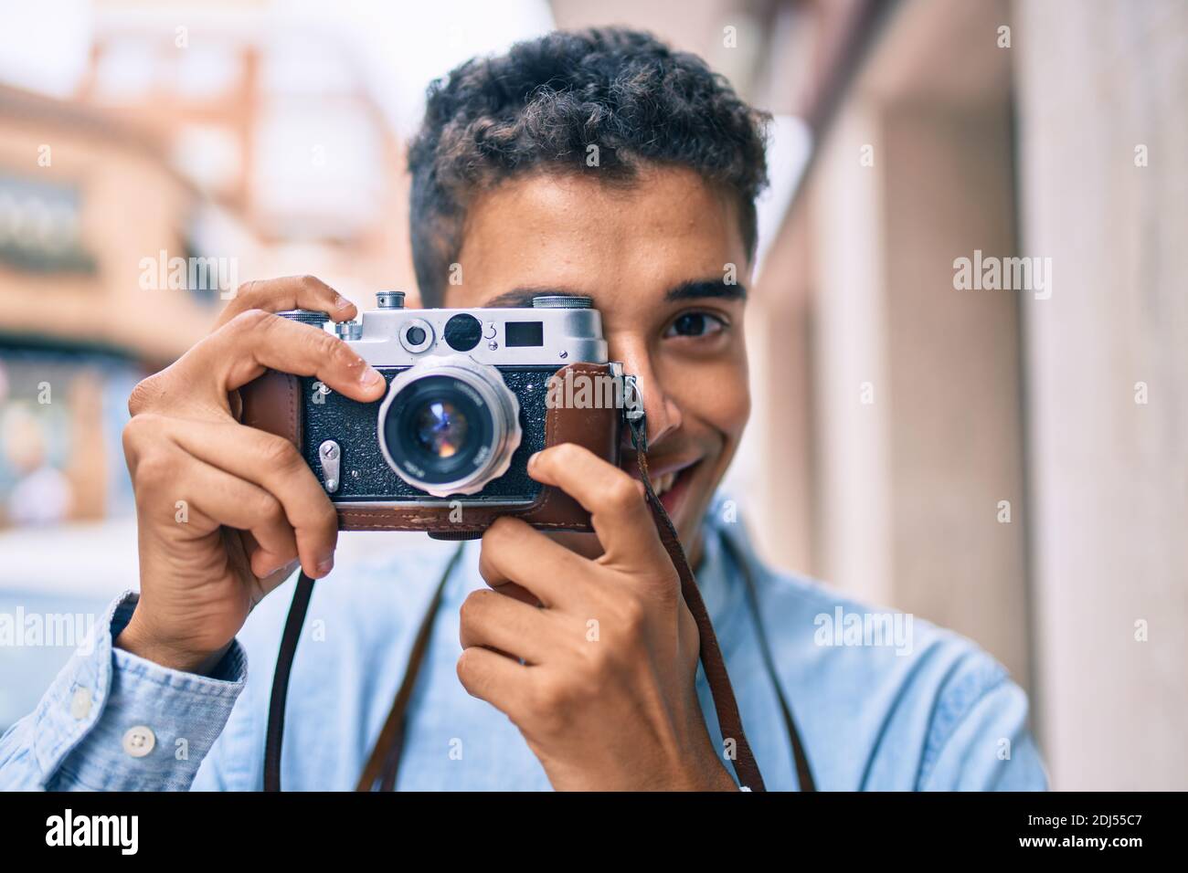 Young latin tourist man smiling happy using vintage camera walking at ...