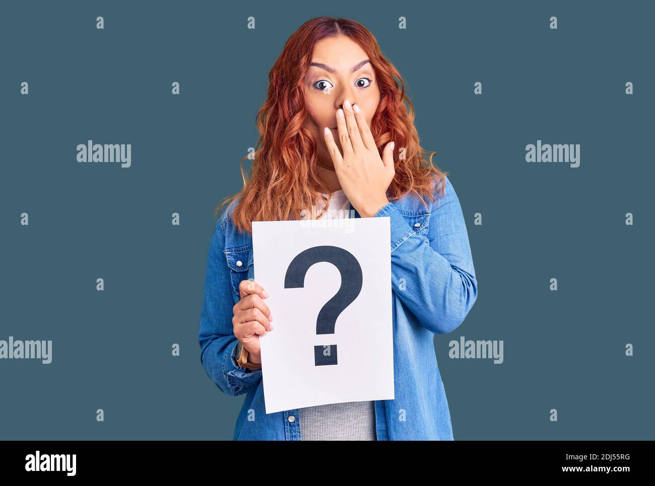 Young latin woman holding question mark covering mouth with hand ...