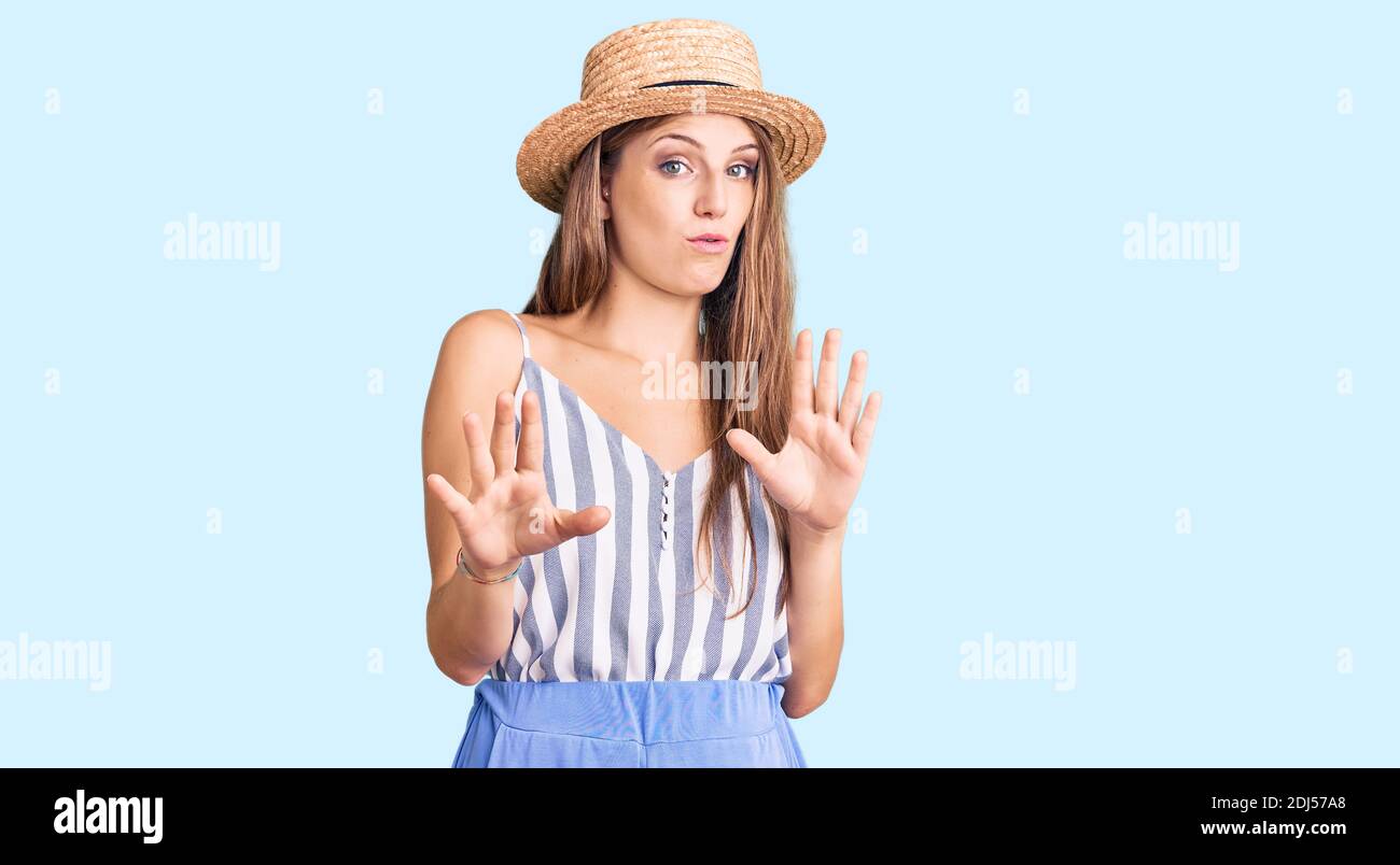 Young beautiful blonde woman wearing summer hat moving away hands palms ...