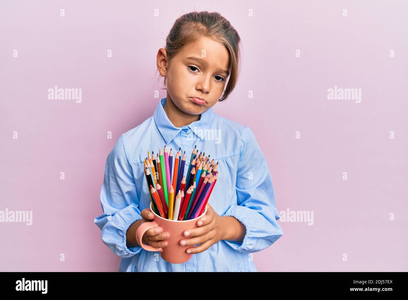 Little beautiful girl holding colored pencils depressed and worry for ...