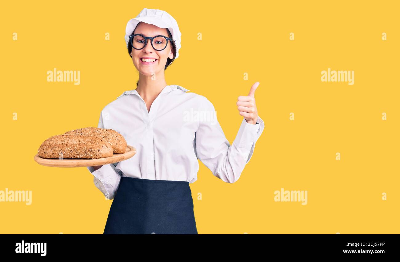 Beautiful brunette young woman wearing baker uniform holding homemade ...
