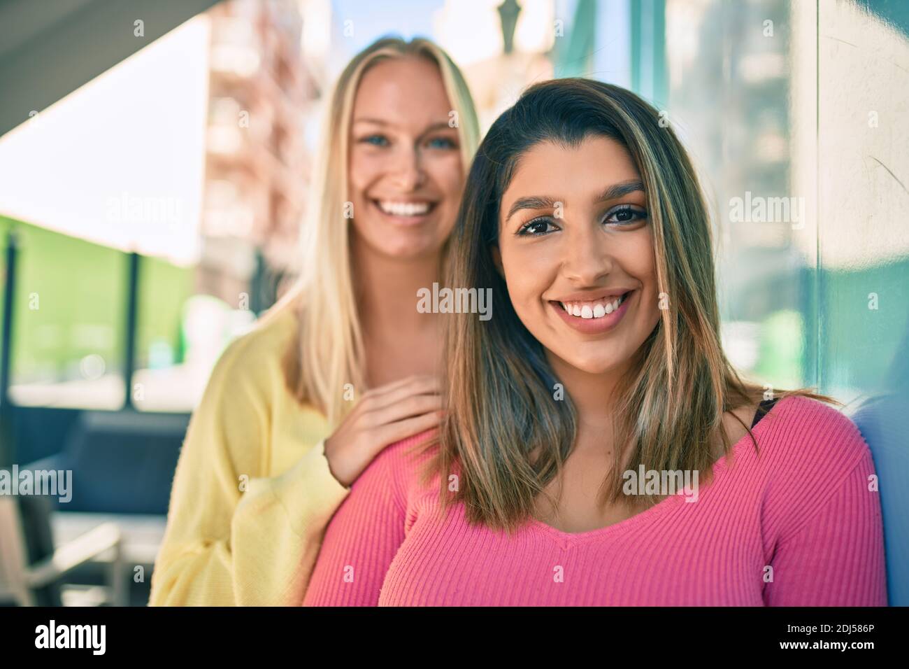 Two beautiful and young girl friends together having fun at the city ...
