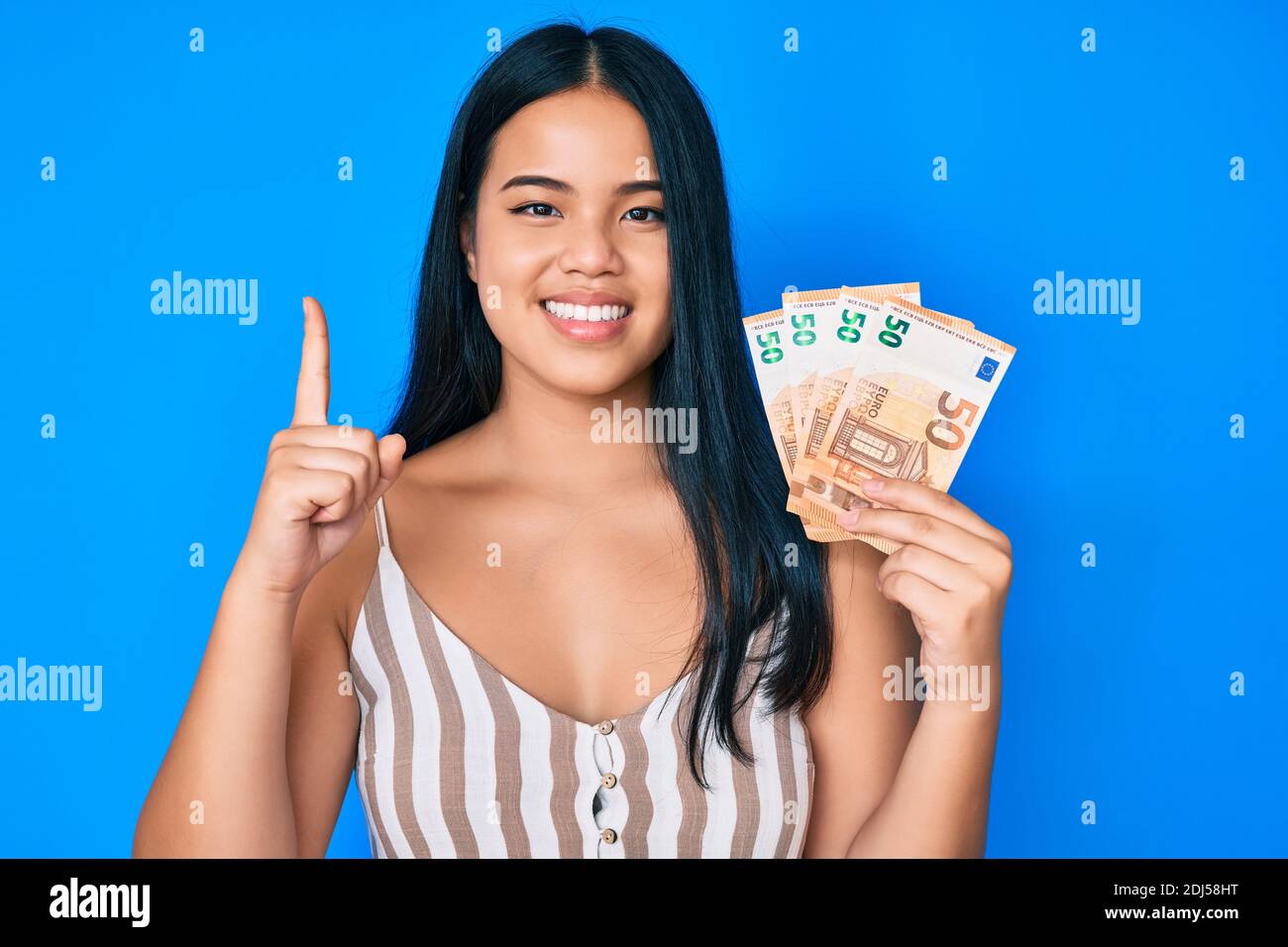 Young beautiful asian girl holding euro banknotes smiling with an idea ...