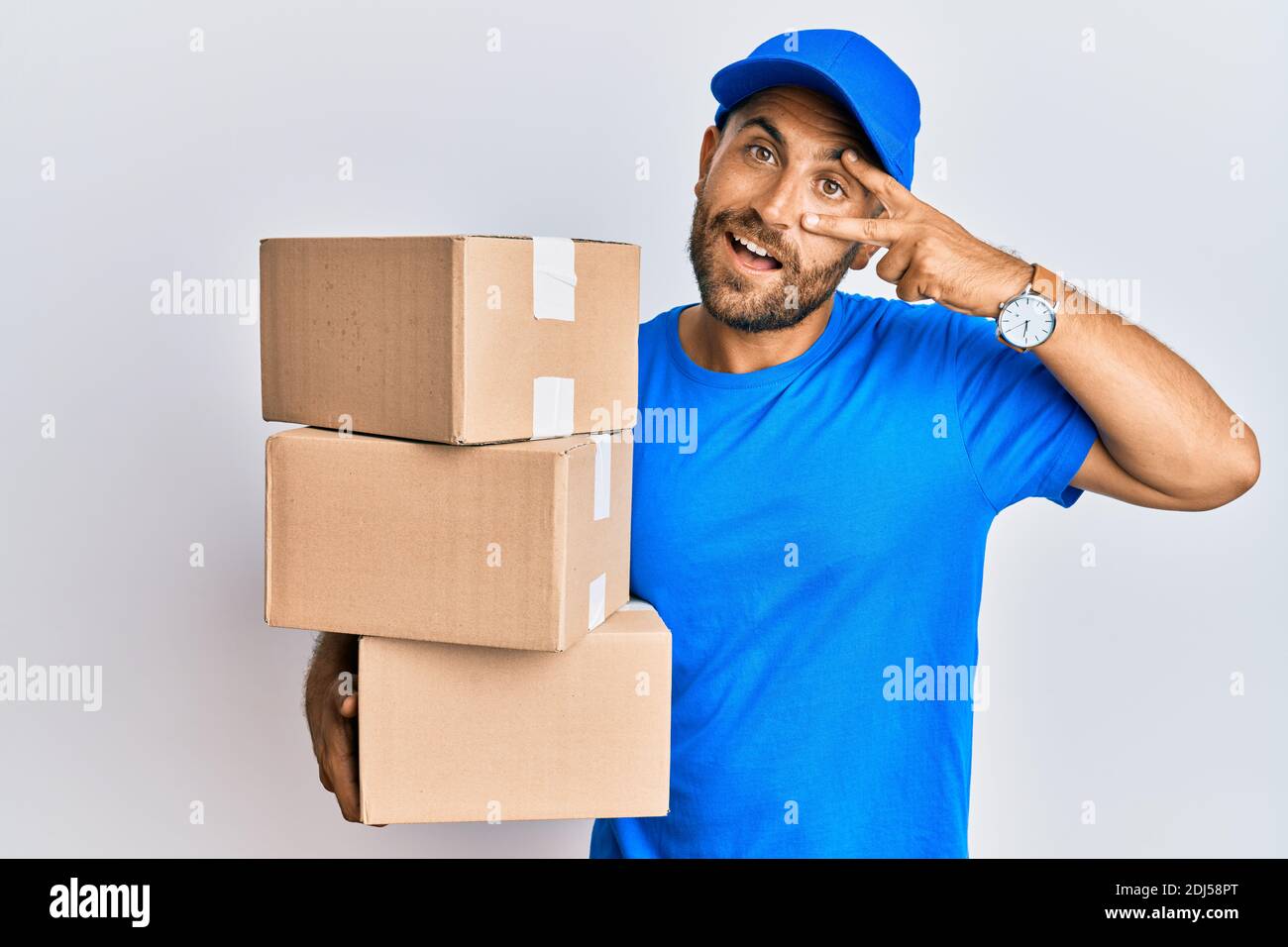 Handsome man with beard wearing courier uniform holding delivery ...