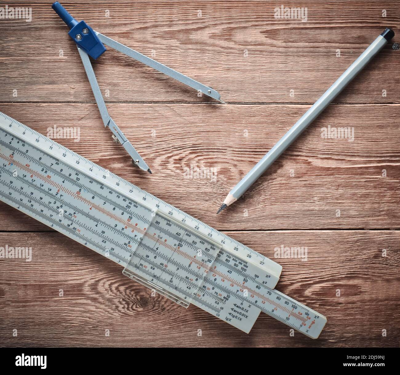 Logarithmic ruler, compasses, pencil on a wooden table. Stationery for ...