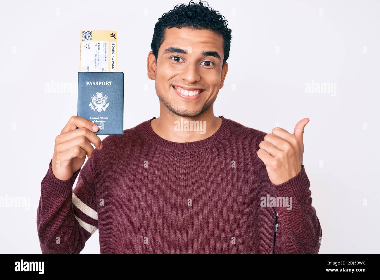 Young handsome hispanic man holding boarding pass and passport pointing ...