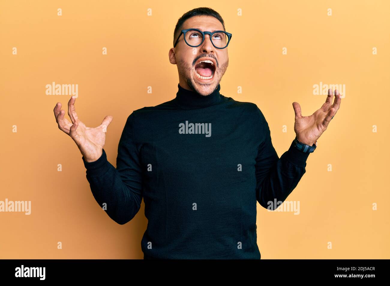 Handsome man with tattoos wearing turtleneck sweater and glasses crazy ...