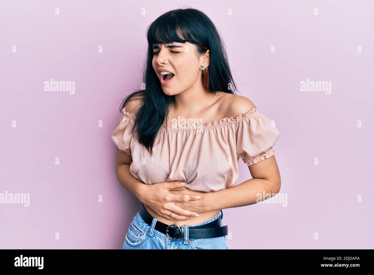 Young hispanic girl wearing casual clothes with hand on stomach because ...