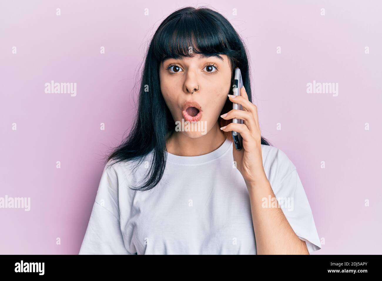 Young hispanic girl having conversation talking on the smartphone ...