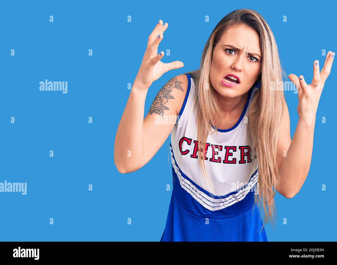 Young beautiful blonde woman wearing cheerleader uniform shouting ...