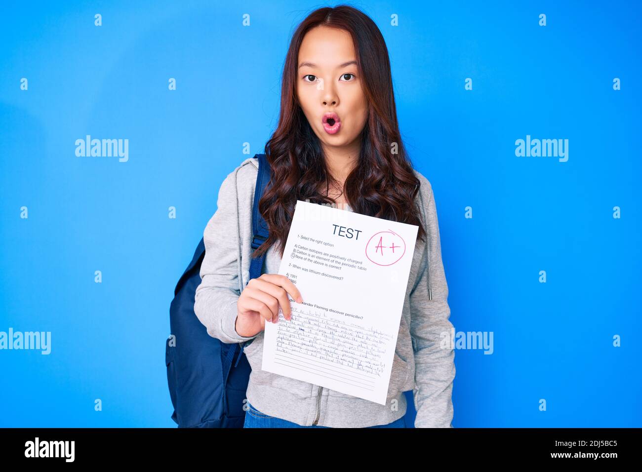 Young beautiful chinese girl showing a passed exam scared and amazed ...