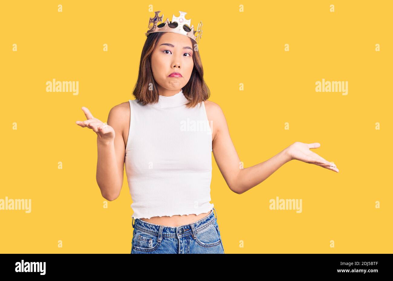 Young Beautiful Chinese Girl Wearing Princess Crown Clueless And Confused Expression With Arms