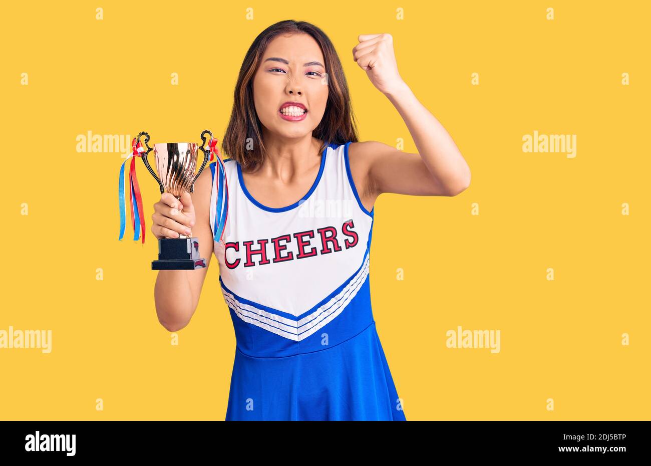 Youn beautiful asian girl wearing cheerleader uniform holding champion ...