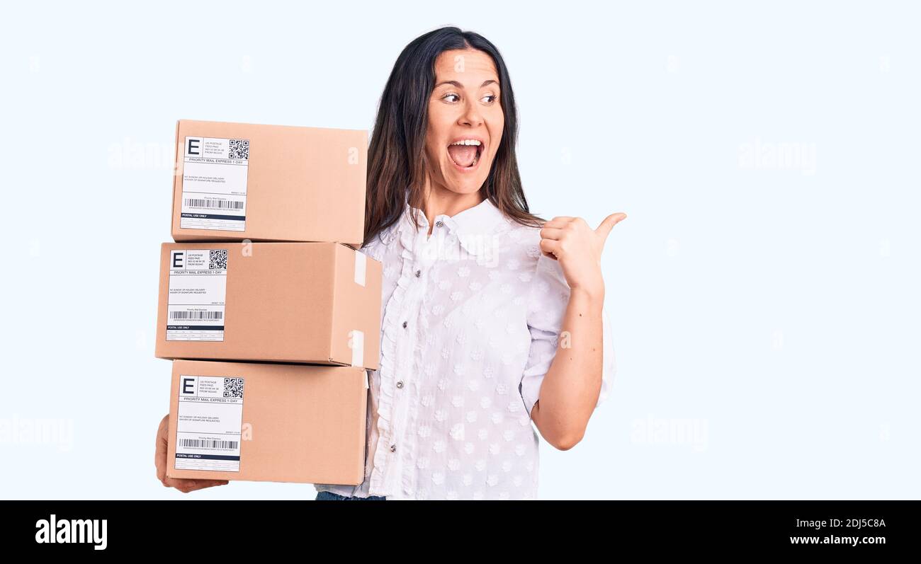 Young beautiful brunette woman holding delivery cardboard package ...