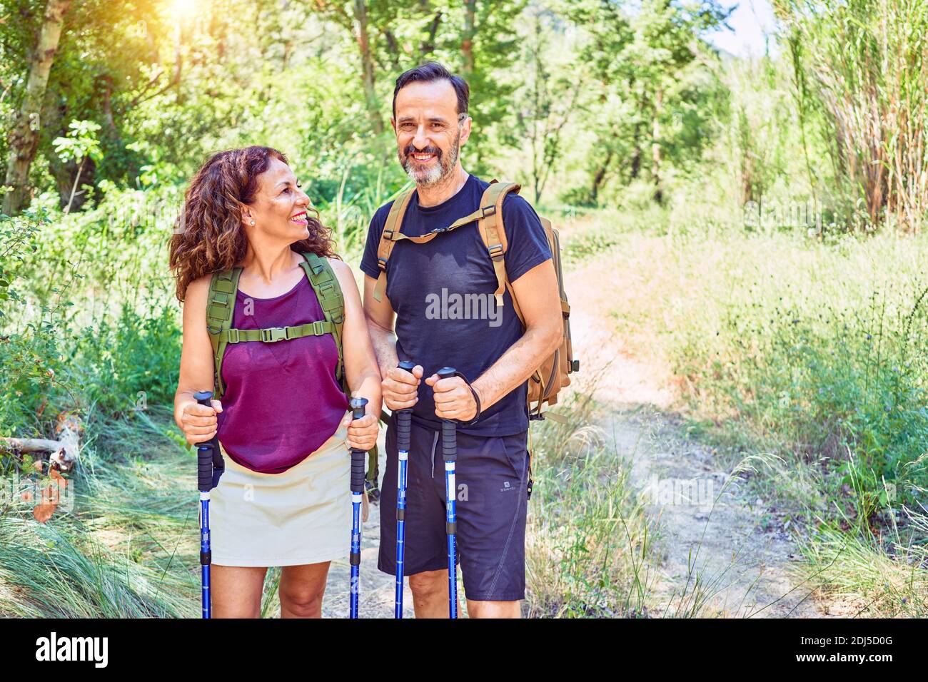 Beautiful couple of hiker wearing backpack smiling happy. Standing with ...