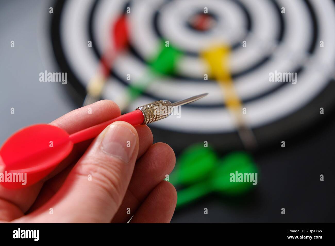 a hand throws darts on a dartboard, a hand holding a dart, a colorful ...
