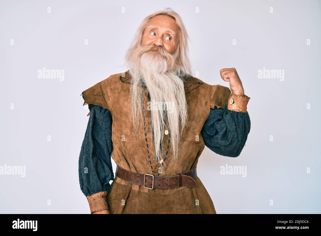 Old senior man with grey hair and long beard wearing viking traditional ...