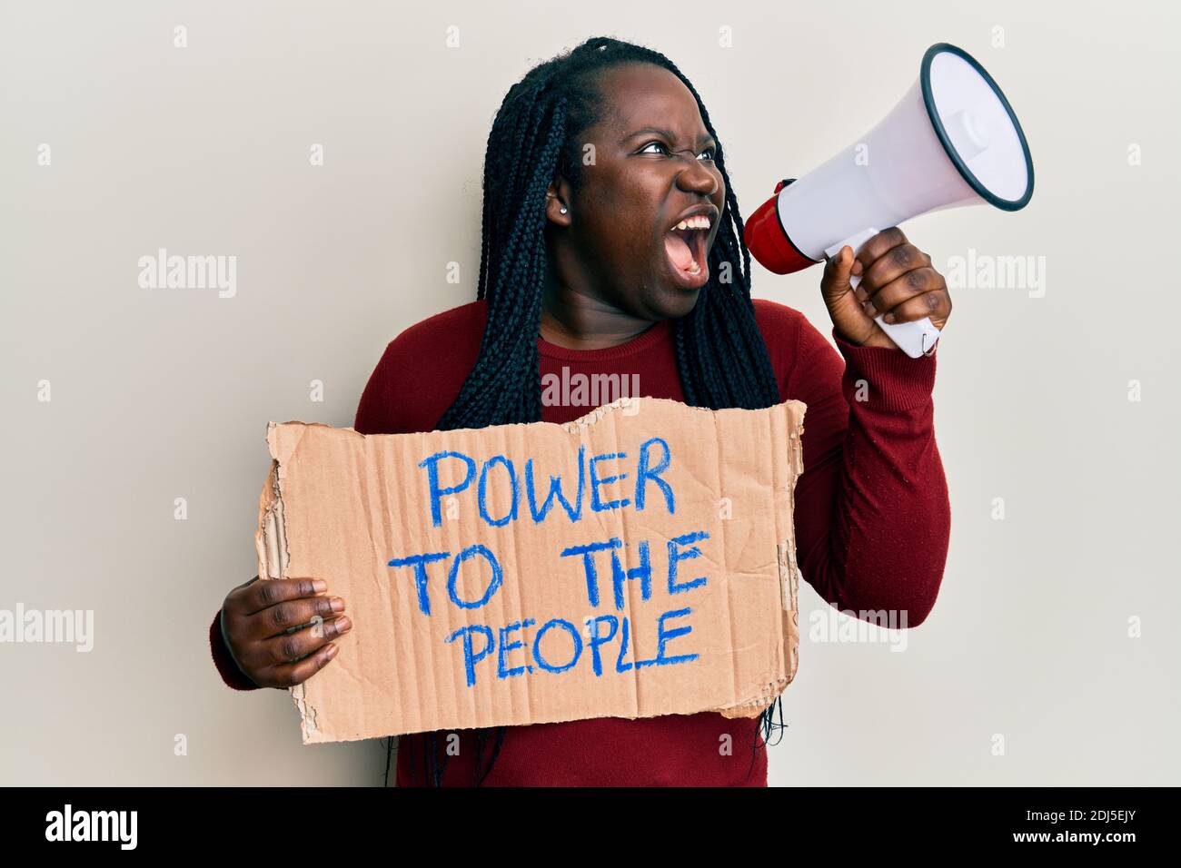 Young black woman with braids holding power to the people banner and ...
