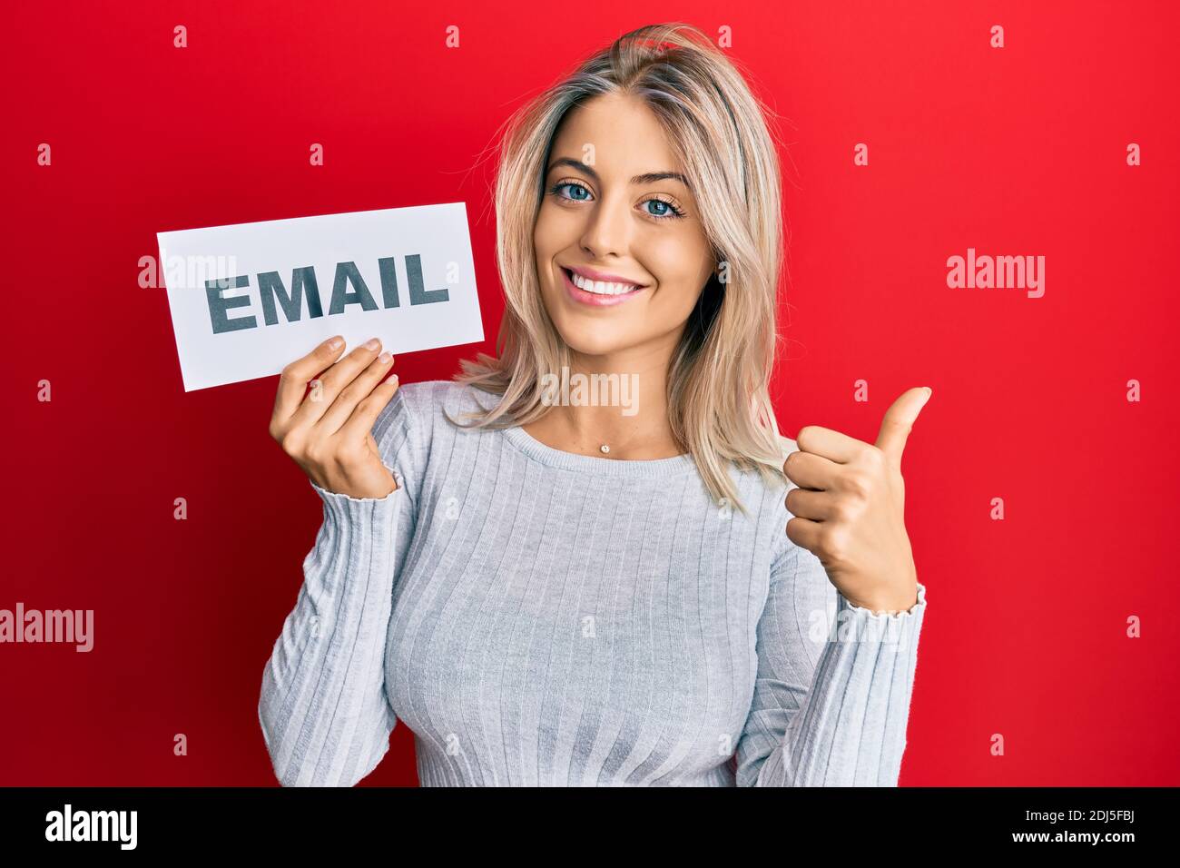 Beautiful blonde woman holding paper with email address smiling happy ...