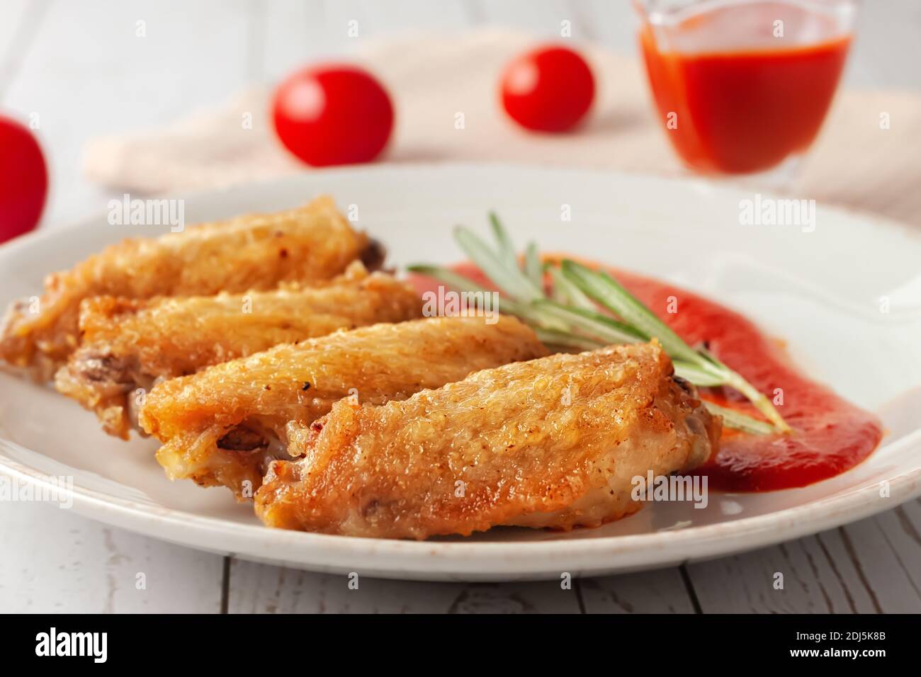 Freshly cooked buffalo wings closeup with tomato sauce and tomatoes ...