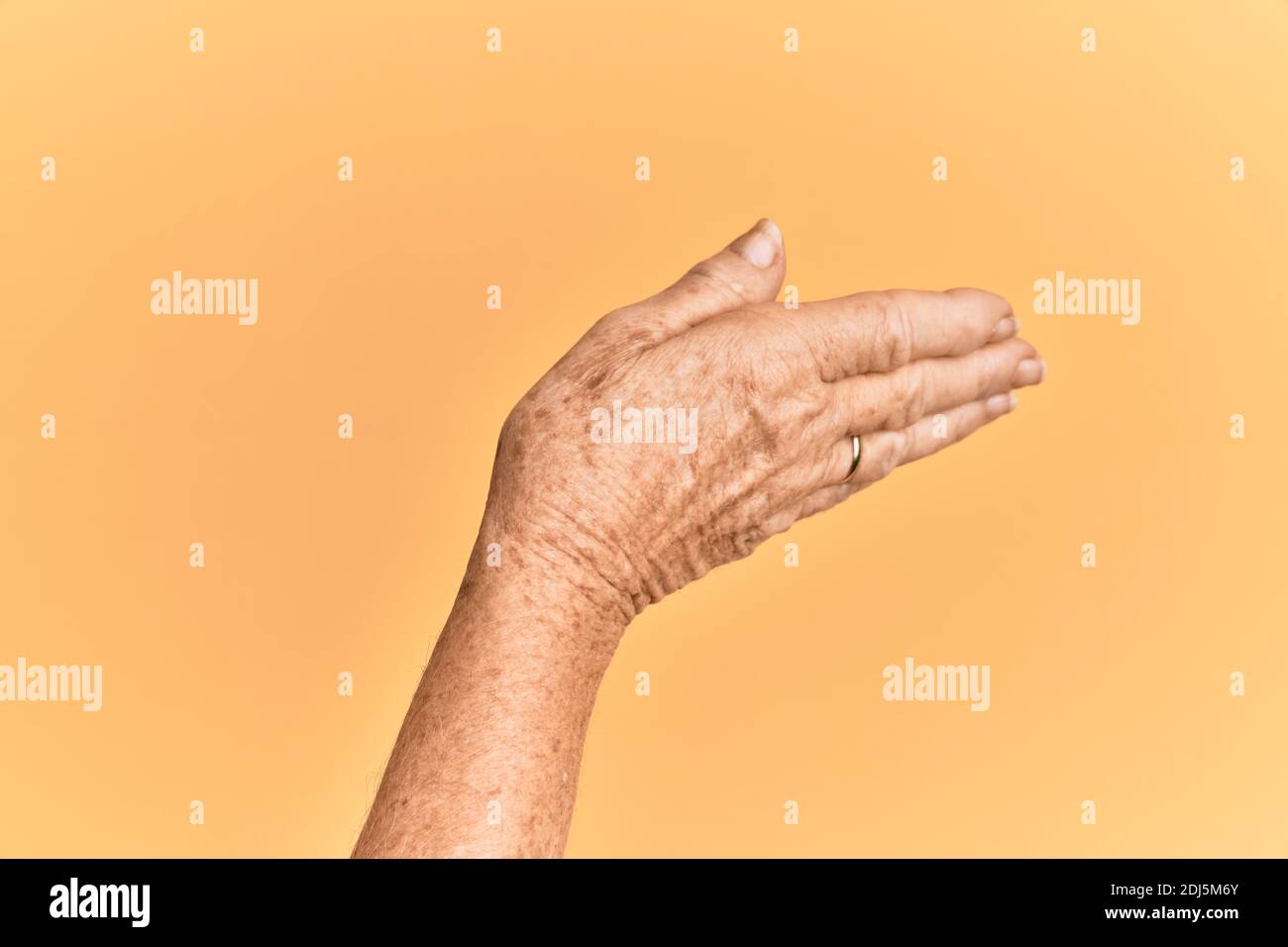 Senior caucasian hand over yellow isolated background stretching and ...