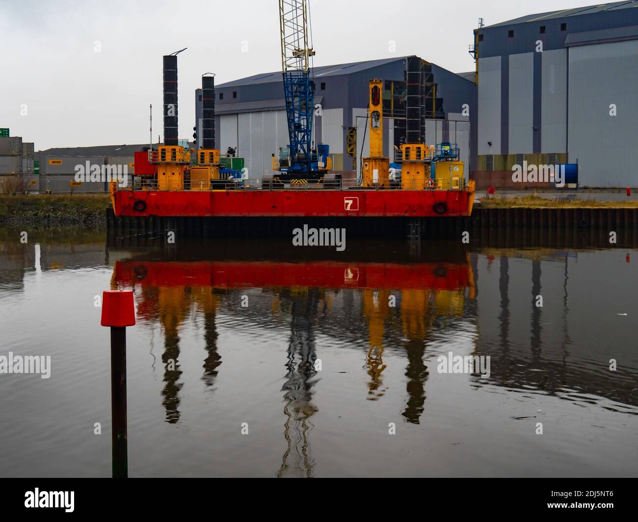 A small Jack up work vessel with a crawler crane on deck parked on the ...
