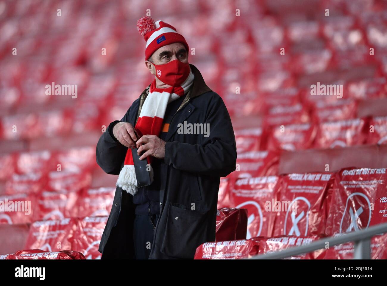 An Arsenal fan wearing a face mask takes his seat for the match, before ...