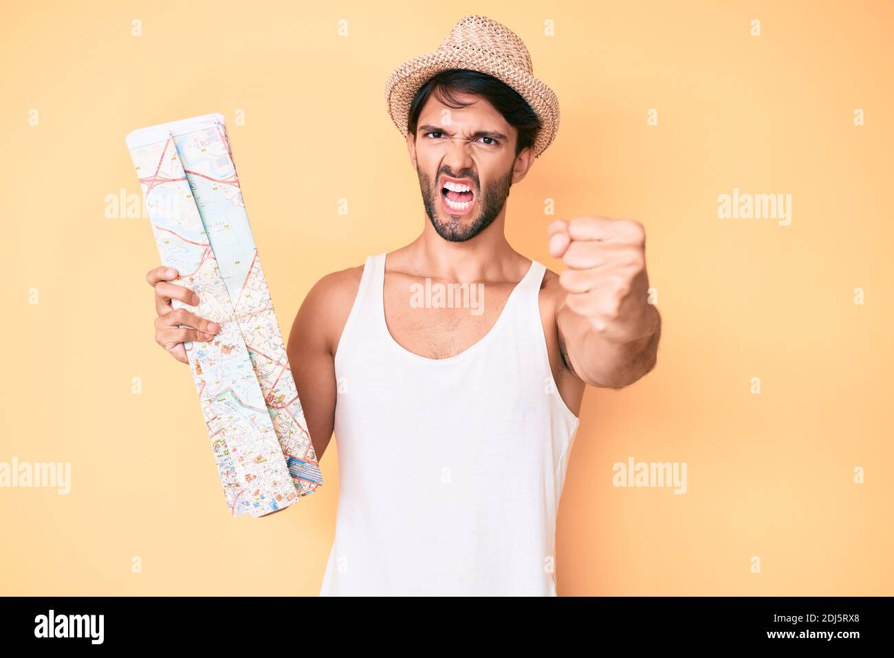 Handsome hispanic man holding city map for summer trip annoyed and ...