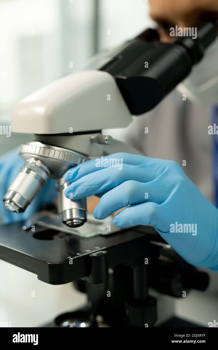 Gloved hand of scientific laboratory worker or researcher fixing ...
