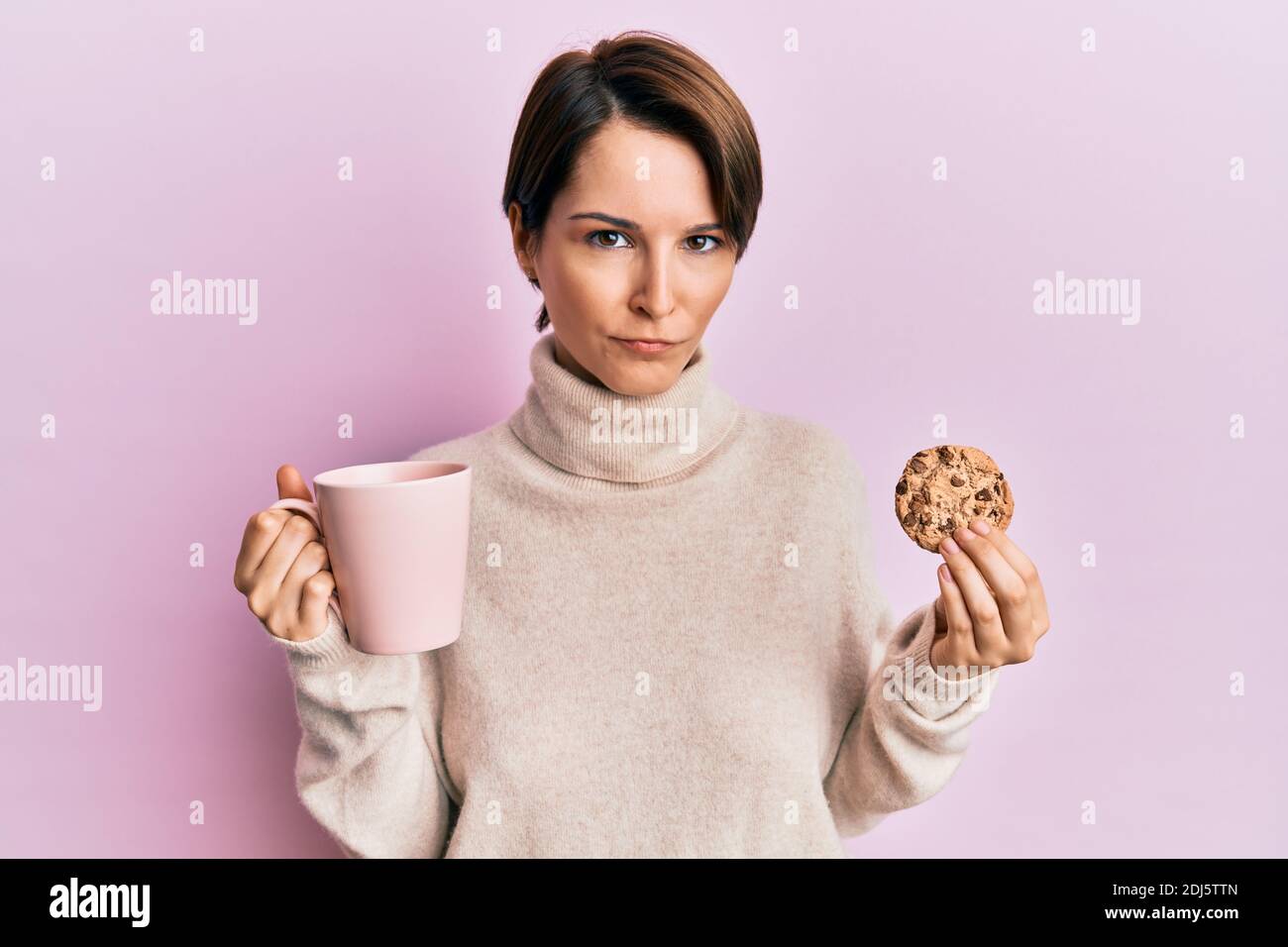 Young brunette woman with short hair drinking a cup of coffee and ...