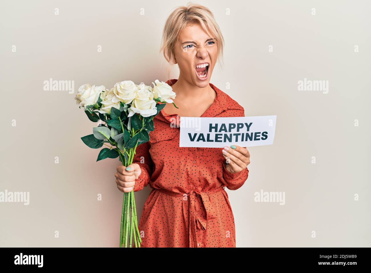 Young blonde girl holding flowers and paper with happy valentines ...