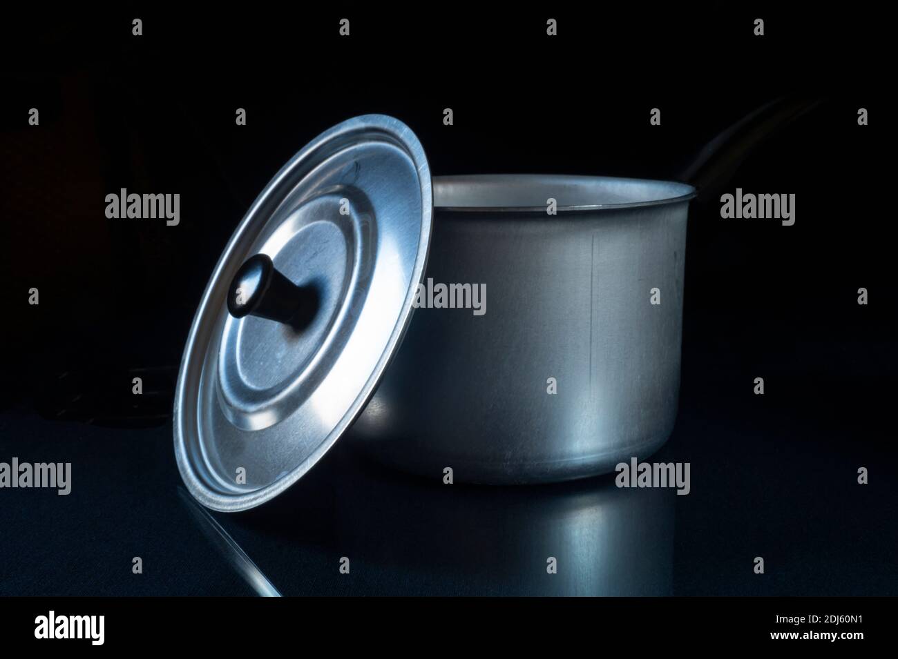 The Saucepan with lid rests upon turn blue the table with reflection ...