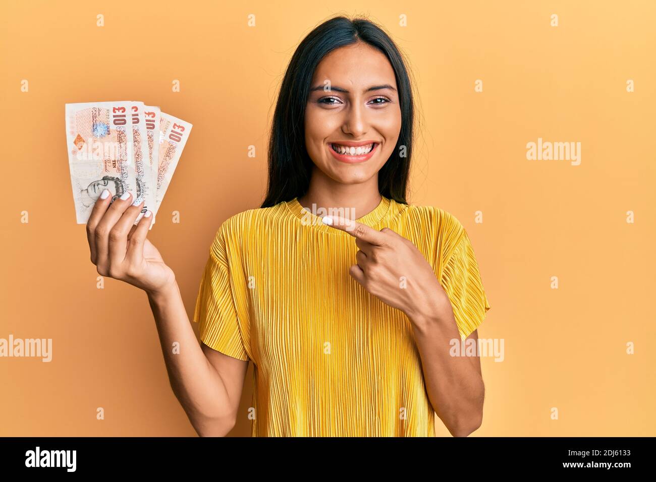 Young brunette woman holding 10 united kingdom pounds banknotes smiling ...