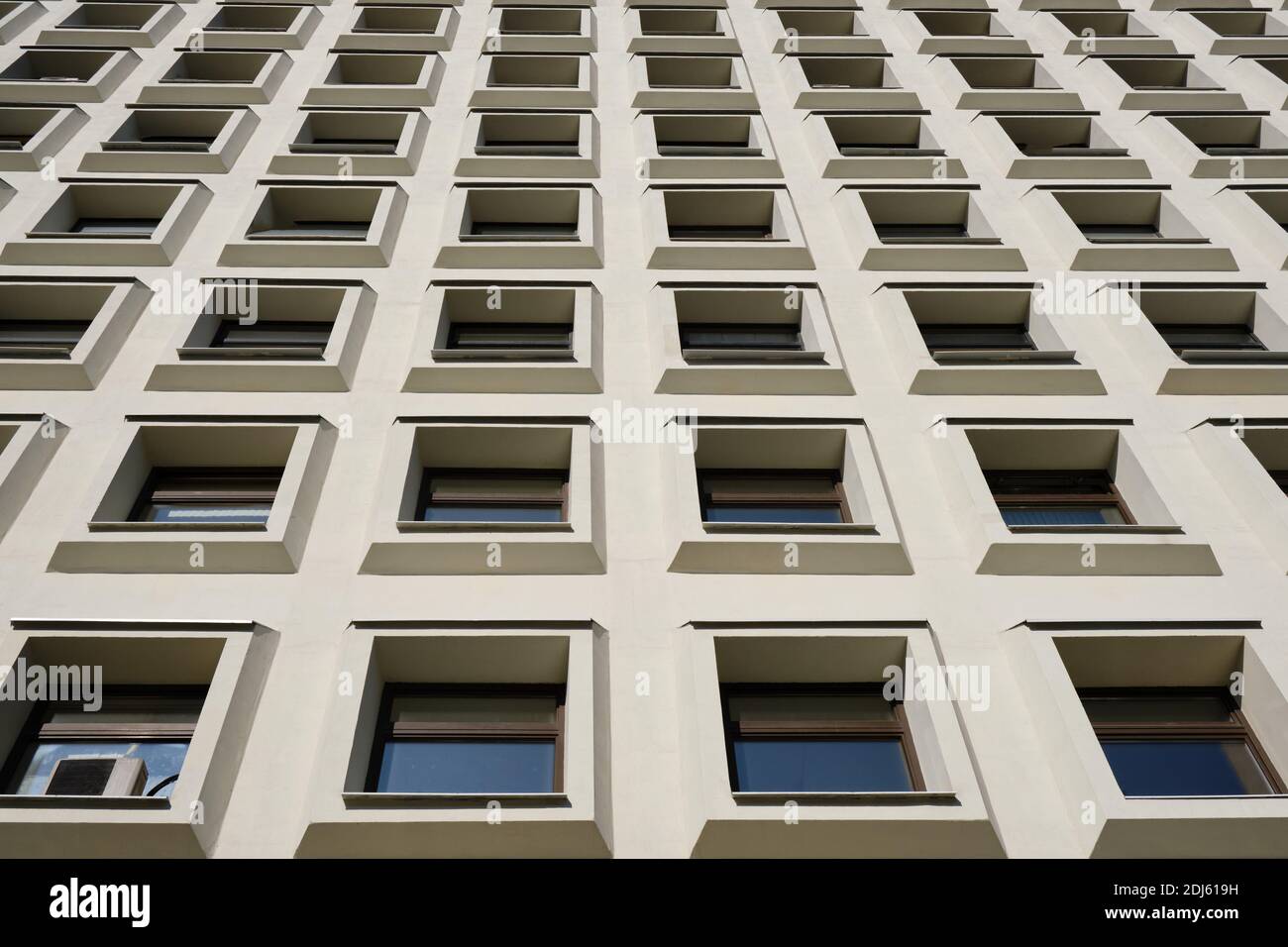 Identical square windows of a concrete building with air conditioning ...