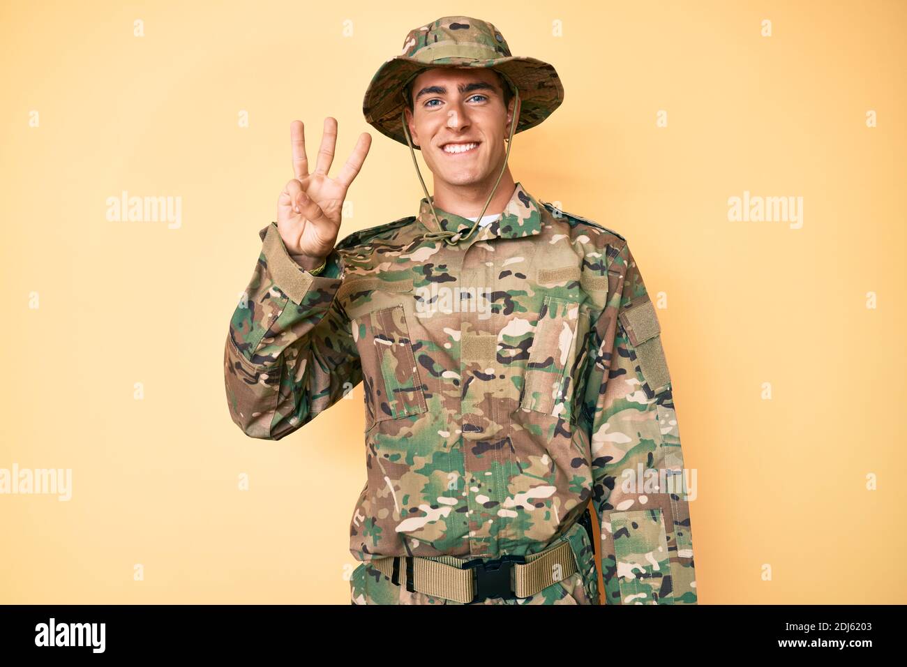 Young handsome man wearing camouflage army uniform showing and pointing ...