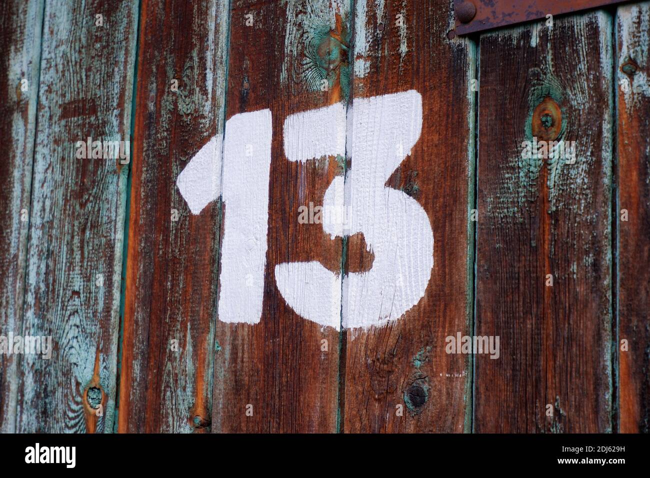 Number thirteen on an old abandoned brown colour wooden gate in ...