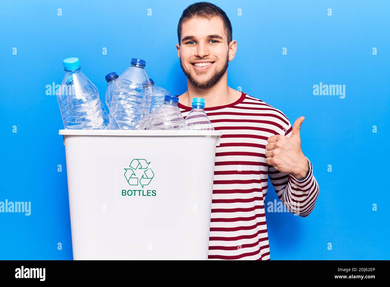 Young handsome man recycling plastic bottles smiling happy and positive ...